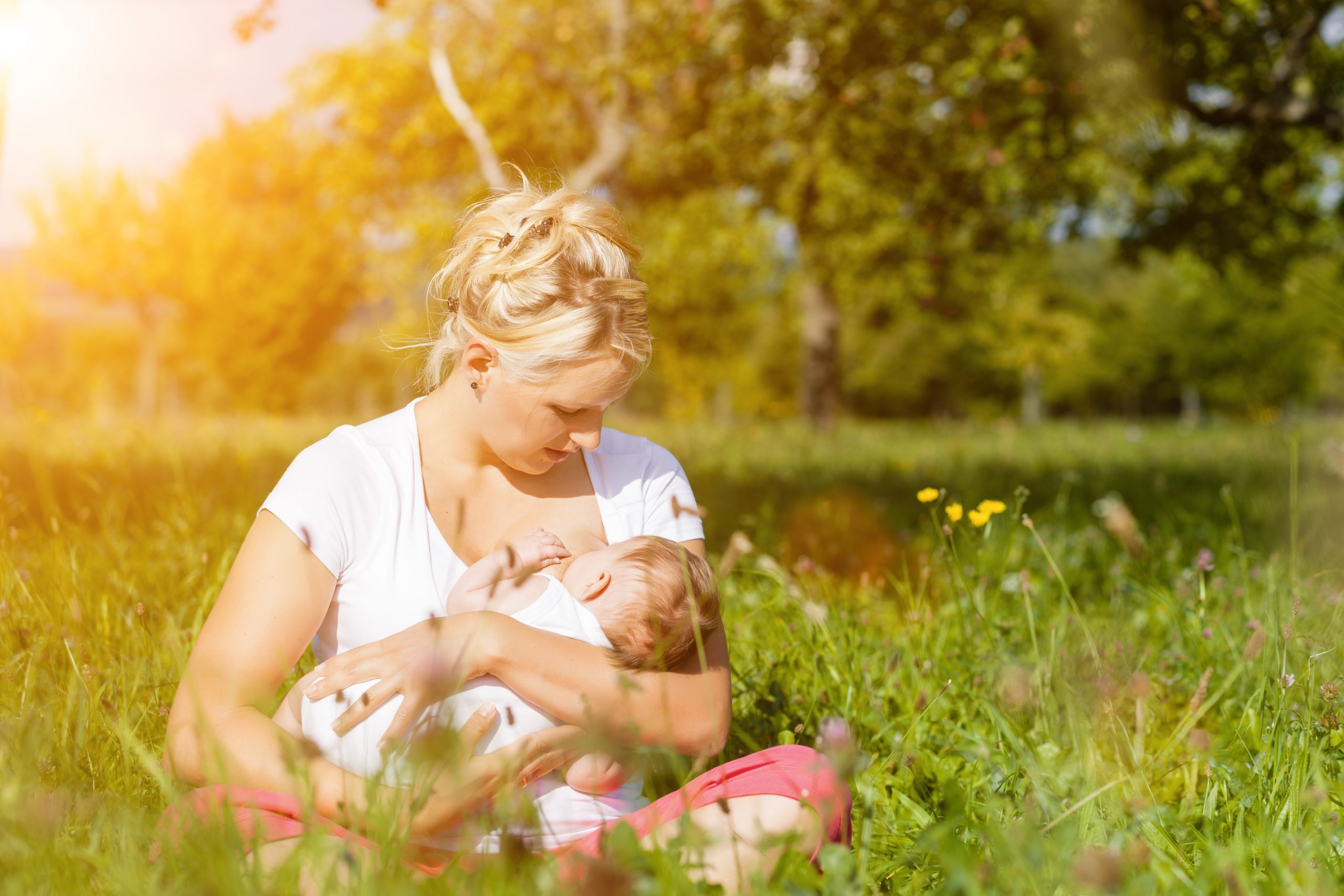 Mother nursing baby on meadow - Mommyz Love